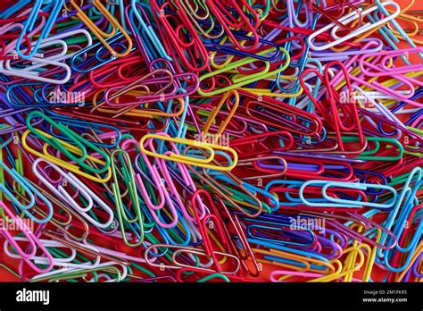 Random Stack Of Mutli Colored Wire Plastic Coated Paper Clips On A Red