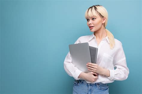 흰 셔츠와 청바지를 입은 짧은 머리를 한 젊은 금발의 백인 여성은 복사 공간을 배경으로 업무용 노트북과 노트북을 들고 있다 사업 이념 20 24세에 대한 스톡 사진 및 기타