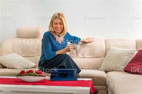 거실에서 소파에 앉아 디지털 태블릿 스톡 사진을 사용하는 성인 쾌활한 여성 40 49세에 대한 스톡 사진 및 기타 이미지 40 49세 가정 생활 거실 Istock