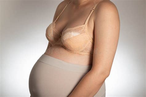 A Pregnant Woman With A Big Belly And A Bra With Liners Against The