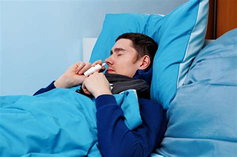 침대에 누워있는 동안 비강 스프레이를 사용하는 아픈 사람의 이미지 건강관리와 의술에 대한 스톡 사진 및 기타 이미지 건강관리와 의술 나잘 스프레이 눈 감기 Istock