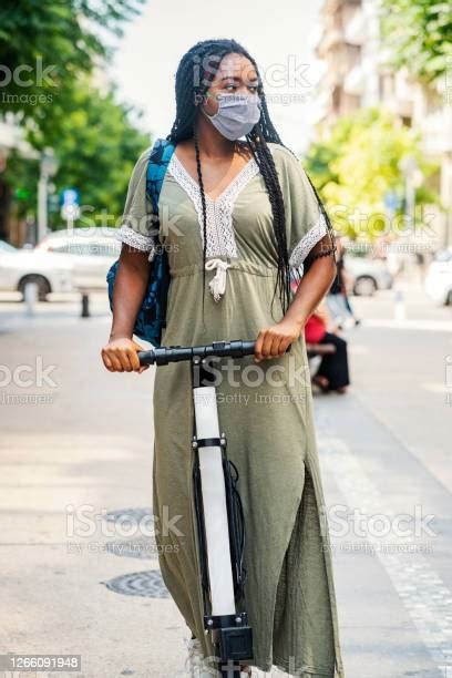 보호 얼굴 마스크를 착용하고 도시를 운전하기 위해 전기 스쿠터를 사용하는 젊은 여성 20 24세에 대한 스톡 사진 및 기타