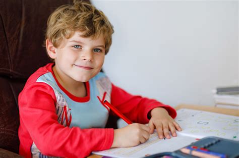 집에서 귀여운 행복 학교 아이 소년의 초상화 숙제를 만들기 작은 아이는 실내에서 다채로운 연필로 씁니다 초등 학교와 교육 문자 및 숫자 쓰기 학습 아이 고등학교 이하에 대한