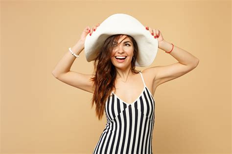 흑백 줄무늬 드레스 모자 서에 쾌활 한 여자의 초상화 옆으로 찾고 스튜디오에서 파스텔 베이 지 배경에 고립 사람들은 진심으로 감정 라이프 스타일 개념입니다 복사 공간을 모의