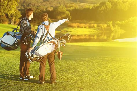 목가적인 골프 코스에서 두 명의 젊은 남성 골퍼가 잠시 멈춥습니다 골프 선수에 대한 스톡 사진 및 기타 이미지 골프 선수