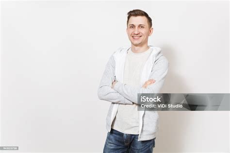 T 셔츠와 가벼운 운동복에 젊은 잘생긴 웃는 남자 학생 건너 가슴 그의 팔에 고립 된 흰색 배경에 기 뻐 합니다 감정 좋은 분위기의 개념입니다 광고에 대 한 공간을 복사