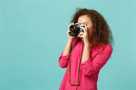 스튜디오에서 파란색 청록색 벽 배경에 고립 된 레트로 빈티지 사진 카메라에 사진을 복용 캐주얼 옷에 젊은 아프리카 소녀 사람들은