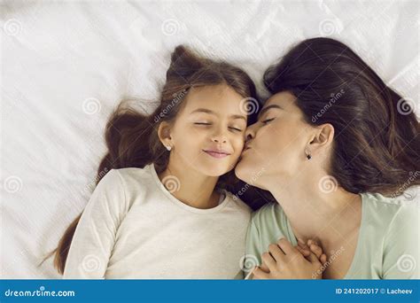 Feliz Madre Besa A Su Hija En La Mejilla Mientras La Despierta En La Ma Ana Imagen De Archivo