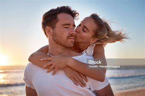 데이트 휴가 또는 여름 여행에서 해변에서 사랑 커플 및 뺨 키스 해변에서 키스하는 남자와 여자의 일몰 애정 또는 로맨스 해안에서 야외에서 함께 유대감을 형성하고 양질의
