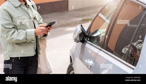 The Woman Unlocks A Free Floating Car Sharing Service Using Her Smartphone On The Street In The