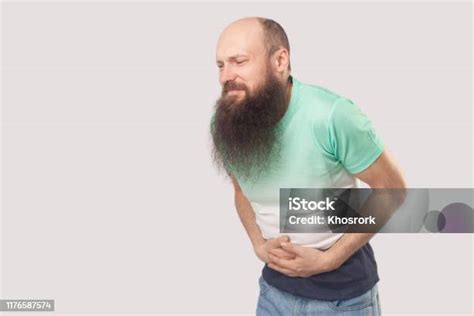 복통 밝은 녹색 티셔츠에 긴 수염을 가진 아픈 중년 대머리 남자의 초상화 그의 고통스러운 배를 들고 나쁜 느낌 건강관리와 의술에 대한 스톡 사진 및 기타 이미지 Istock