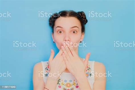 블루 스튜디오 배경에 재미 귀여운 소녀 밝은 감정적인 여성 초상화입니다 손으로 입을 덮고 있는 여자 악의 3 원숭이 개념을 말한다 가리기에 대한 스톡 사진 및 기타 이미지