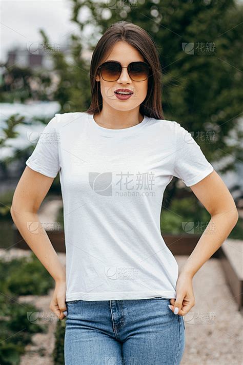 时尚的黑发女孩穿着白色t恤和眼镜对着街道，城市服装风格。街头摄影