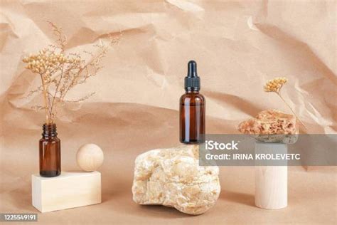 돌에 피펫 나무 기하학적 모양과 베이지 색 종이 배경에 말린 꽃갈색 유리 병에 세럼 또는 에센셜 오일 천연 유기농 스파 코스메틱 컨셉 프론트 뷰 갈색에 대한 스톡 사진 및