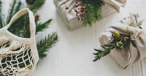 녹색 가지가 있는 린넨 패브릭으로 싸인 세련된 크리스마스 선물과 소박한 나무 배경에 녹색 가문비나무가 있는 재사용 가능한 쇼핑백 제로 폐기물 크리스마스 휴일 지속 가능한