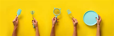 부엌 도구를 들고 손 잡고 주방 도구 체 롤링 핀 그릇 체 브러시 거품 및 베이킹에 대 한 주걱 및 노란색 배경에 요리 음식