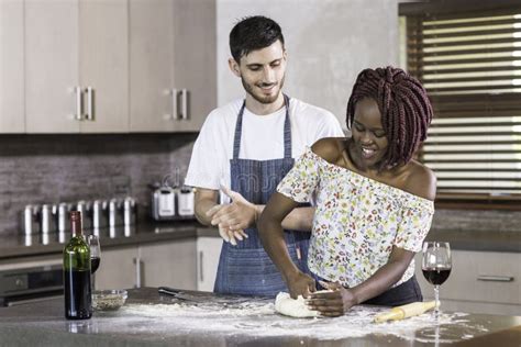 Happy Young Mixed Race Couple Drinking Wine Cooking Dinner In Kitchen