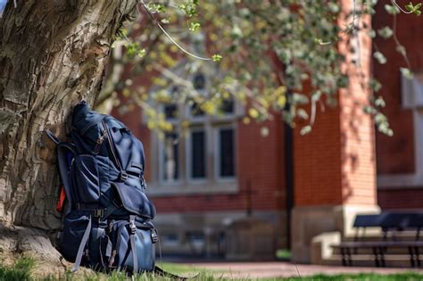 lone backpack leaning against a tree with lecture halls behind