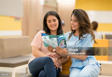 쾌활 한 여자 간호사는 병원의 대기실에서 그녀가 보여주는 책자를 보고 책자에 대한 스톡 사진 및 기타 이미지 책자 보기