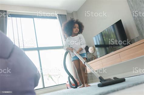 침실에서 바닥을 진공 청소기로 청소하고 집안일로 엄마를 돕고 집을 청소하는 어린 아이 집에서 어머니를 도우면서 진공 청소기를 사용하는 어린 소녀 2 3 살에 대한 스톡 사진