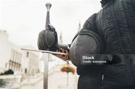 긴 중세 날카로운 검과 보호 마스크 클로즈업과 검은 역사적인 펜싱 갑옷을 입은 전사 역사적인 아이템과 오래된 전통과 전투 복원