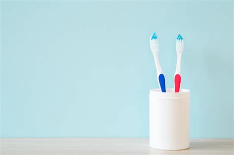 파스텔 블루 벽에 선반에 플라스틱 유리에 두 개의 칫 솔 남성과 여성의 치아 위생 개념입니다 텍스트 인용 격언 또는 로고에 대 한 빈 장소 닫습니다 전경에 대한 스톡 사진