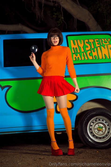 A Young Woman Dressed As Velma Dinkley From Scooby Doo Stands