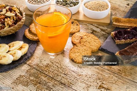 오렌지 주스 슬라이스 바나나 혼합 말린 과일 채식 비스킷 잼과 채식 헤이즐넛 호박 씨앗 참깨와 해바라기 씨앗의 크림 빵 조각달콤한 채식 아침 식사를위한 나무 테이블 세트