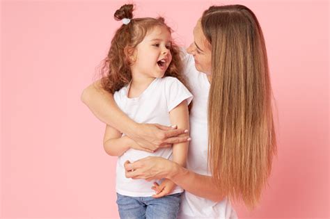 흰색 티셔츠와 청바지를 입은 엄마와 딸이 분홍색 배경을 가지고 놀고 포옹합니다 사랑하는 사람을 돌보아 행복한 모성 2명에 대한 스톡 사진 및 기타 이미지 Istock