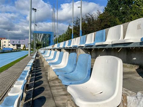Empty Blue And White Stadium Seats Line A Vibrant Blue Running Track