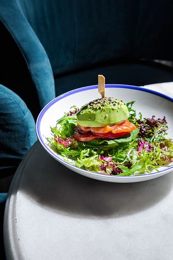 연어 아보카도 참깨 토마토 아루굴라 바질 엔디브 양배추를 소파로 둘러싸인 하얀 테이블 위의 접시에 담은 샐러드 0명에 대한 스톡