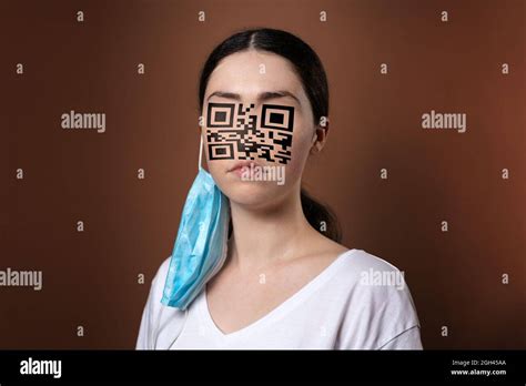 Portrait Of A Woman Wearing Protective Mask With A QR Code Instead Of A Face Brown Background