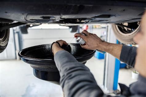 Premium Photo Close Up Of A Mechanic Cleaning Rust On Engine Part While Draining The Oil From