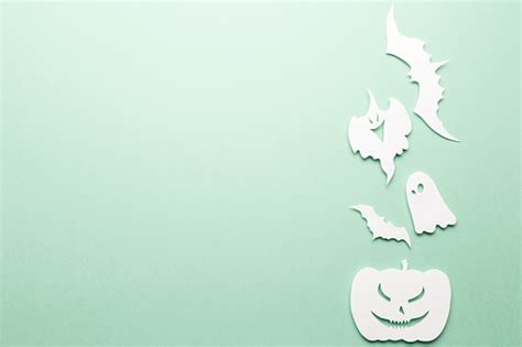 할로윈 장식 파스텔 민트 배경에 할로윈 종이 장식입니다 맨 위 보기 액세서리 장식 할로윈 축제의 플랫 레이 공간을 복사합니다 최소한의 창조적 인 개념 파스텔 색상 10월에