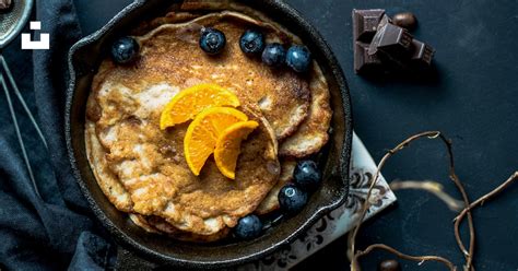 흩어져있는 초콜릿과 커피 콩 옆에 오렌지와 블루 베리를 곁들인 팬케이크 사진 Unsplash의 무료 음식 이미지