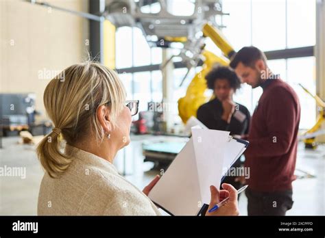 Engineers Collaborating On Robot Programming In A Modern Industrial Facility Focus On