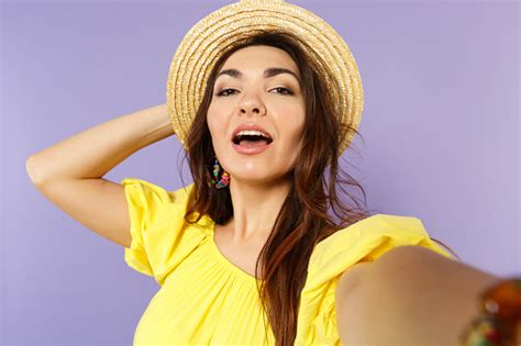 노란 드레스 파스텔 바이올렛 벽 배경에 고립 된 머리에 손을 넣어 여름 모자에 멋진 젊은 여자의 Selfie 샷을 닫습니다 사람들은 진심으로 감정 라이프 스타일 개념입니다