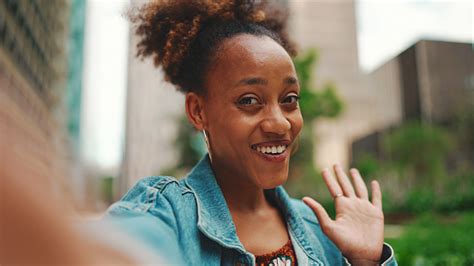 근접 촬영 포트릿 포니 테일과 귀여운 아프리카 소녀 데님 재킷을 입고 스트림 현대 도시 배경에서 스마트 폰에 화상 통화를 만듭니다 감정에 대한 스톡 사진 및 기타 이미지