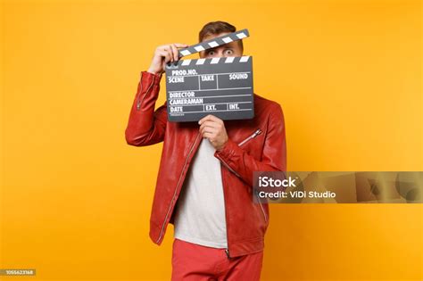초상화 유행 젊은이 빨간색 가죽 자 켓 티셔츠 만들기 Clapperboard 고전적인 흑인 영화를 들고 웃 고 밝은 동향 노란색 배경에 고립 사람들의 라이프 스타일