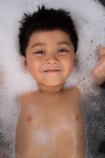 เด็กชายเอเชียถูกล้อมรอบด้วยโฟมฟองอาบน้ํา ภาพสต็อก ดาวน์โหลดรูปภาพตอนนี้ การซัก การดูแล
