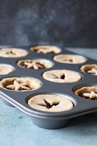 페이스트리 스타 상세 뚜껑을 얹은 조리되지 않은 수제 다진 파이의 이미지 머핀 트레이 행 달콤한 다진 고기 가있는 축제 크리스마스 디저트 쇼트 크러스트 0명에 대한 스톡