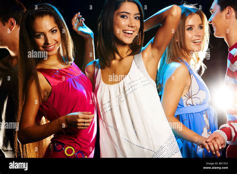 Group Of Fashionable Girls Dancing Energetically In Night Club Stock