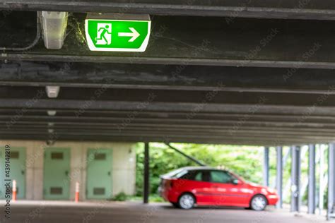 Green Exit Sign With Running Person And Green Arrow Shows Guidance System Signage In A Parking