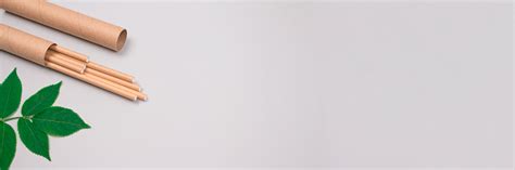 배너 카피 스페이스가있는 밝은 회색 배경에 그 주위에 녹색 잎이있는 크래프트 종이 튜브 또는 용기에 포장 갈색 종이 빨대의 모형 이미지 지속 가능한 라이프 스타일과 제로