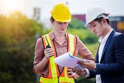 컨테이너 마당에 하드햇 서화물을 착용하고 수입 및 수출화물화물 선박에서 컨테이너 상자를 제어하는 제어를 확인 엔지니어 여성과 사업가 팀워크 컨셉 검사 보기에 대한 스톡 사진