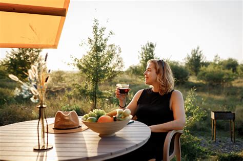 행복한 여성 프리랜서는 화창한 날에 아늑한 글램핑 텐트에서 휴식을 취하면서 전화와 칵테일 통화를 사용합니다 야외 여름 휴가 및