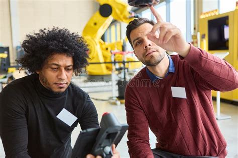 Two Engineers Programming A Robotic Arm In An Industrial Setting Stock Image Image Of