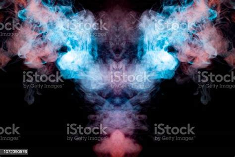 파란색의 배경 귀신의 머리의 모양 또는 검은색 신비로운 외모의 남자에서 빨간색과 녹색 물결 모양의 연기 접지 절연 밝은 추상 패턴 Vape에서 증기의 검은색에 대한 스톡