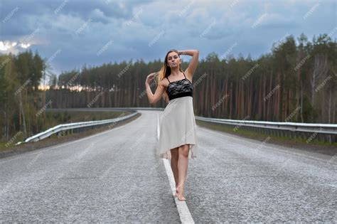 Premium Photo A Girl Barefoot In A Dress Walks Along The Highway In