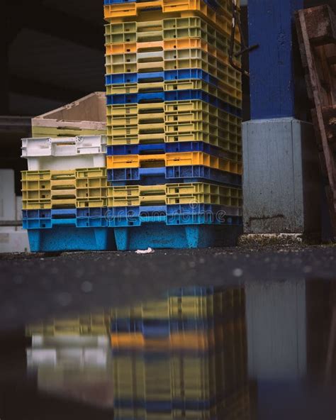 Stack Of Colorful Plastic Crates Reflected In A Puddle In A Fisher